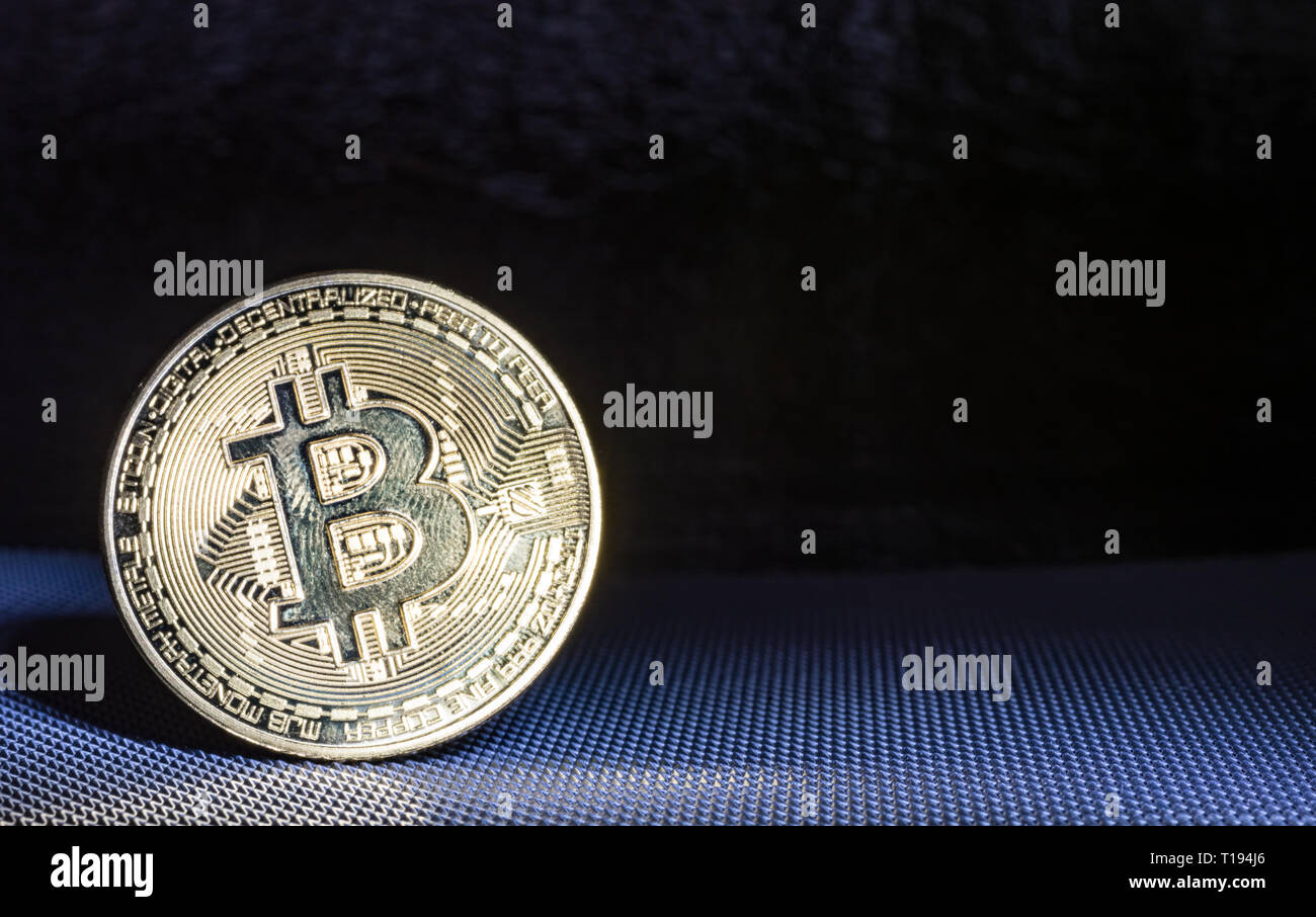 Front view of single golden bit coin on silver metallic dark background ...