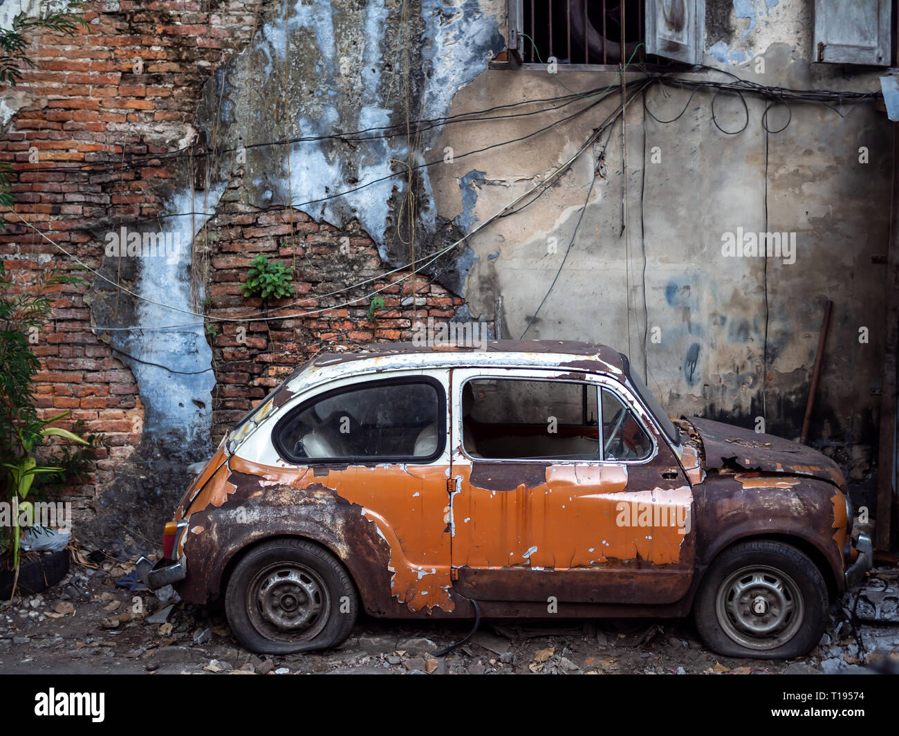Old abandoned rusty car with flat tires on old brick wall background ...