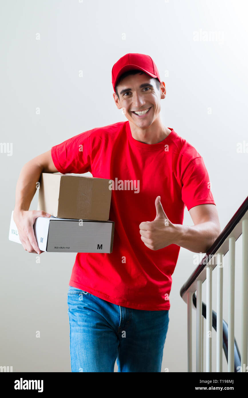 Delivery man holding mail boxes showing thumbsup Stock Photo - Alamy