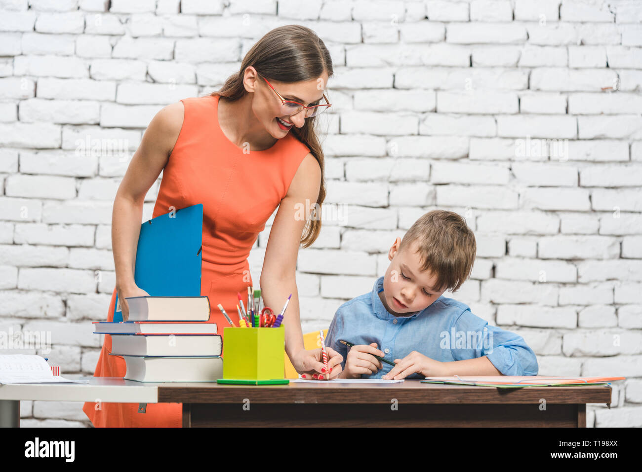 Teacher helping student with difficult task in school Stock Photo - Alamy