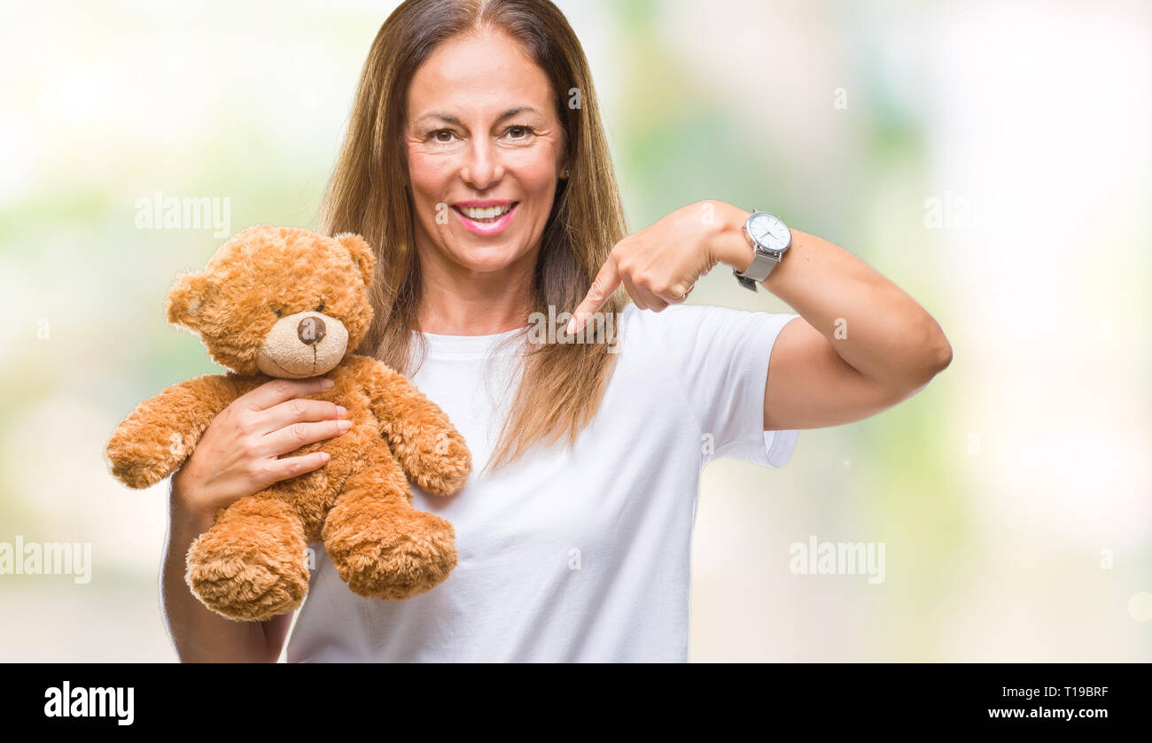 Middle age hispanic woman holding cute teddy bear plush over isolated ...