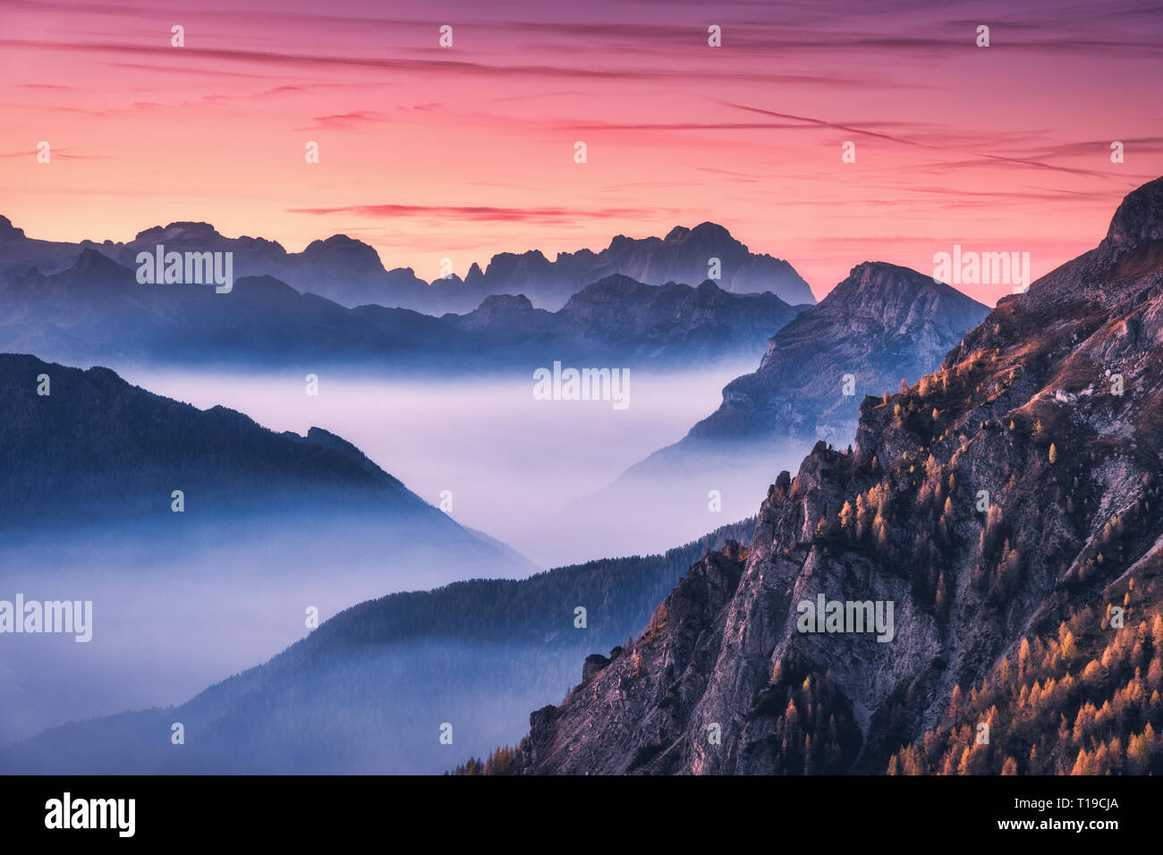Mountains in fog at beautiful sunset in autumn in Dolomites, Italy ...