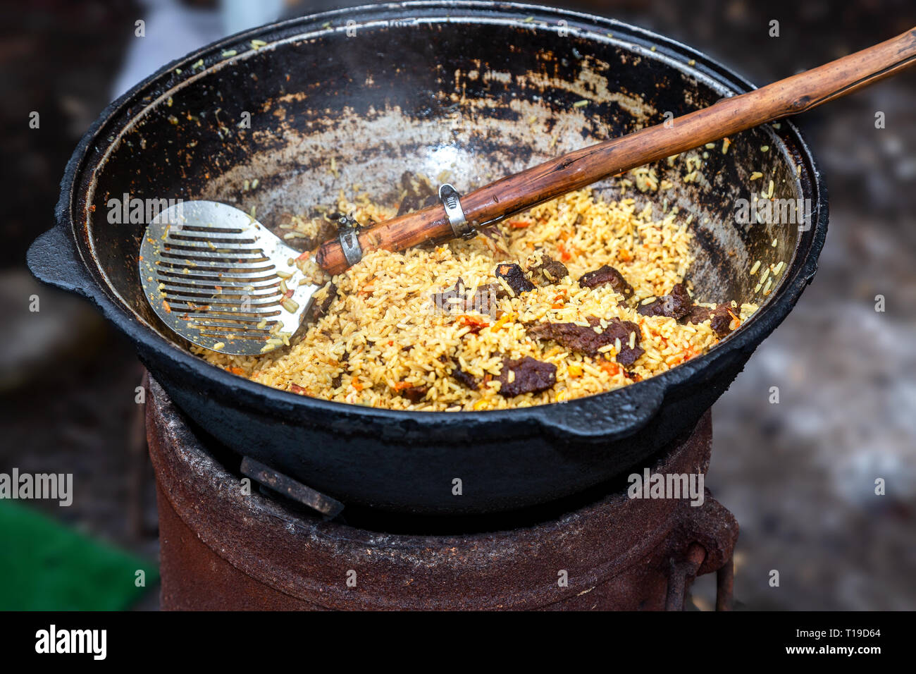 Cooking traditional Uzbek pilaf in a large cauldron outdoors Stock ...