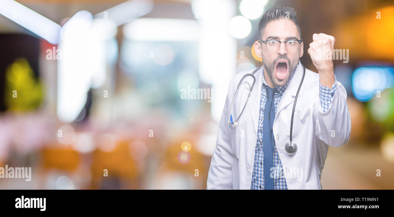 Handsome young doctor man over isolated background angry and mad ...