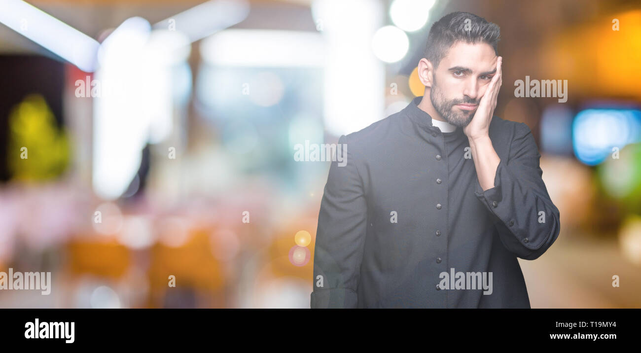 Young Christian priest over isolated background thinking looking tired ...