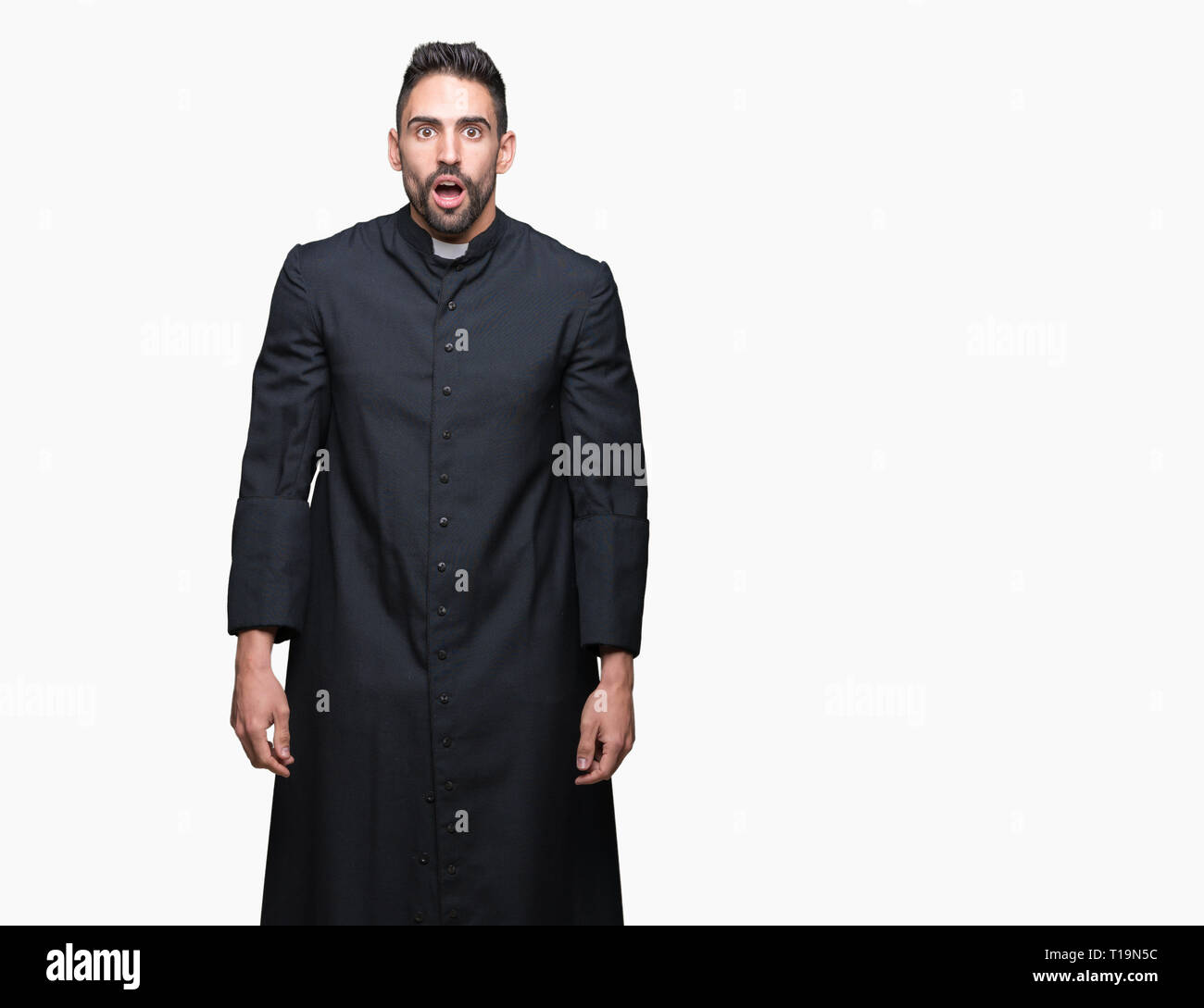 Young Christian priest over isolated background afraid and shocked with ...