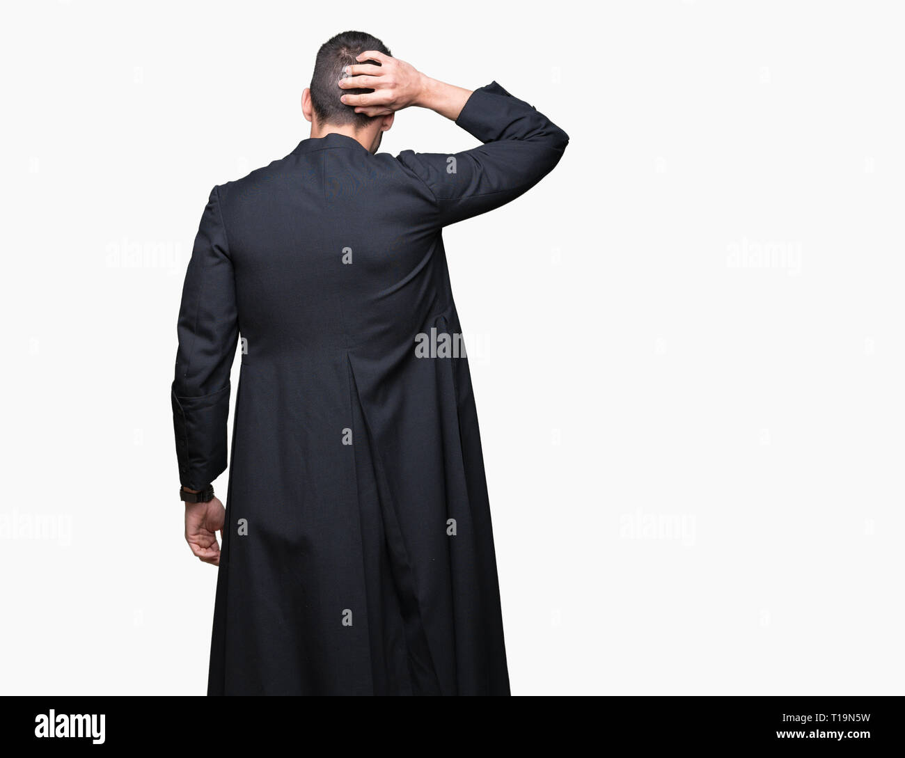 Young Christian priest over isolated background Backwards thinking ...