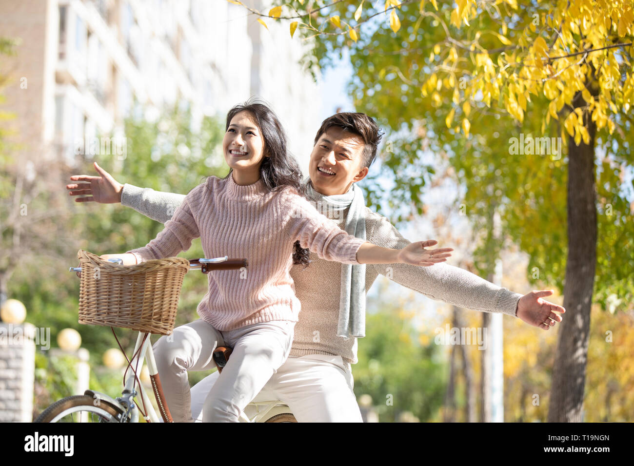 Happy young couple riding bike together on street Stock Photo - Alamy