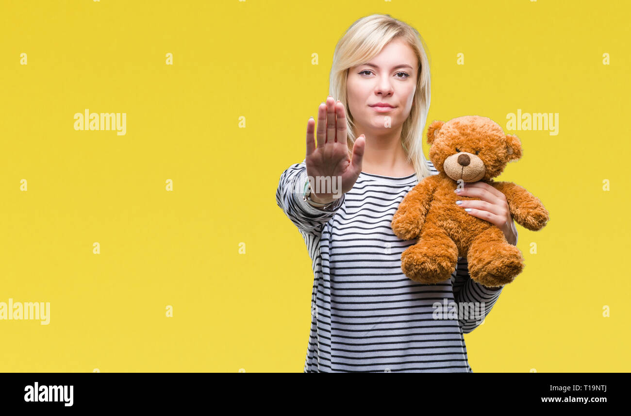 Young beautiful blonde woman holding teddy bear plush over isolated ...