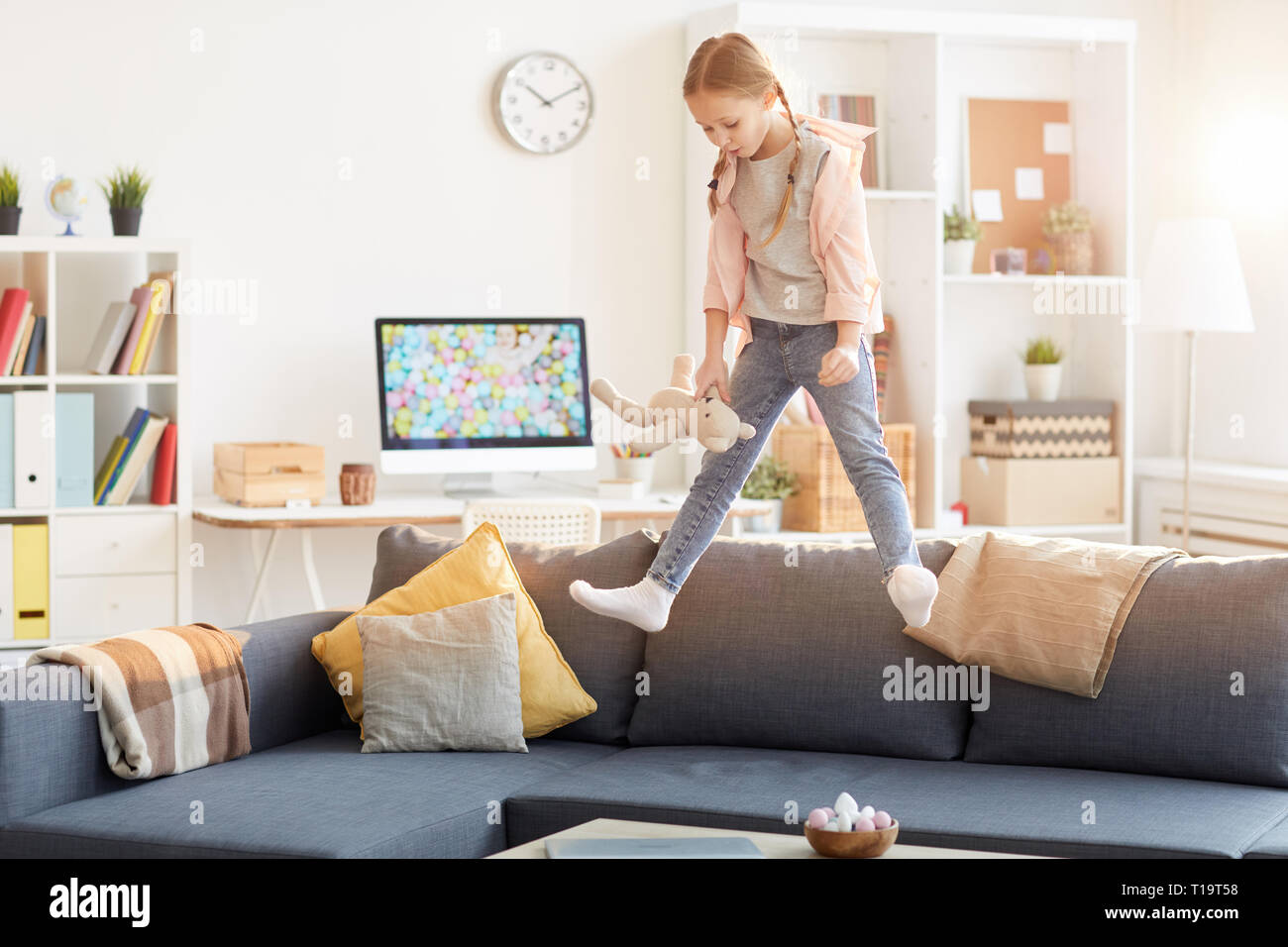 Playful Girl Jumping on Couch Stock Photo - Alamy