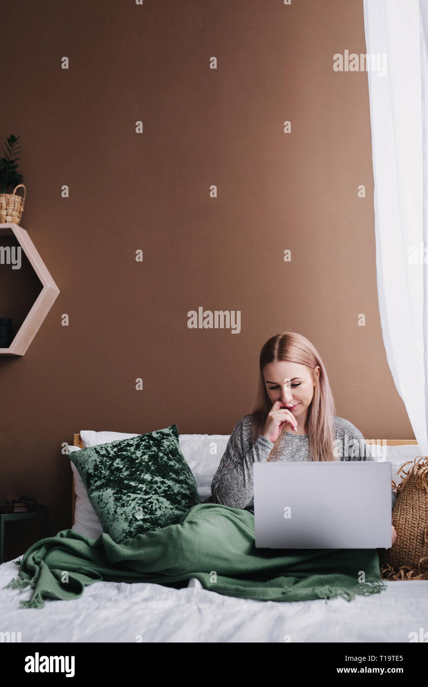 Young woman working on computer in bed. Relaxing at home Stock Photo ...