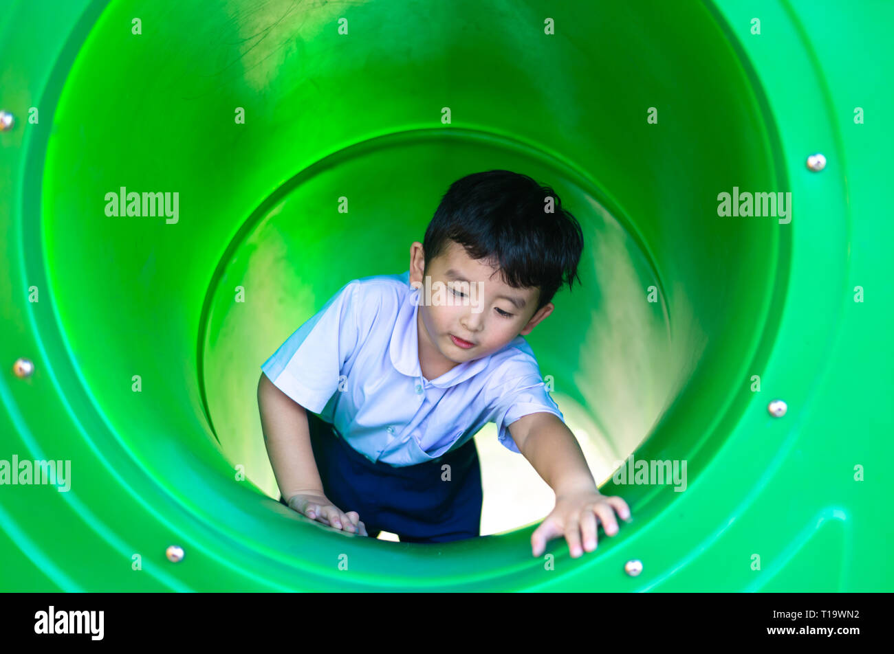 Little Asian kid climbing up the slide at the playground under the ...