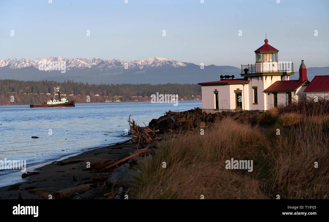 A boat passes West Point Lighthouse in the Puget Sound at Dawn Stock ...