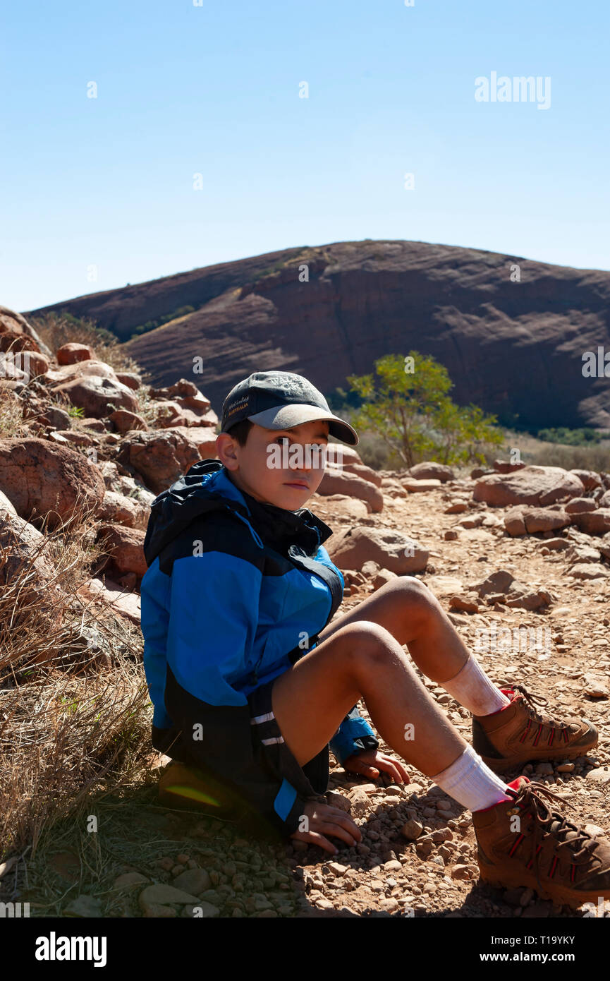 A young boy takes a rest stop o n the Valley of the Winds walk, Kata ...