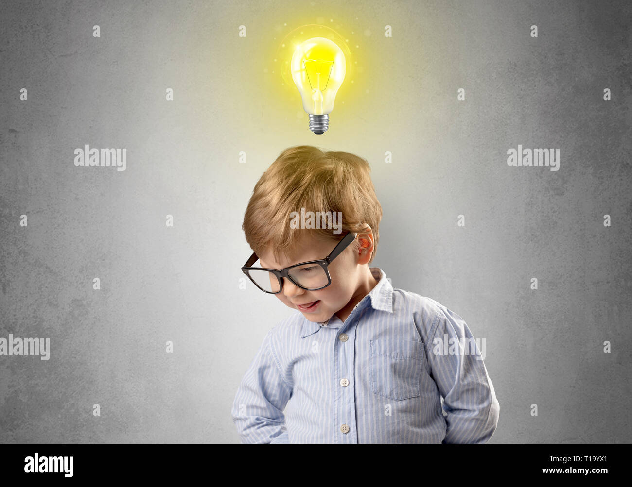 Adorable little kid mull over in front of a grey wall with idea symbol ...