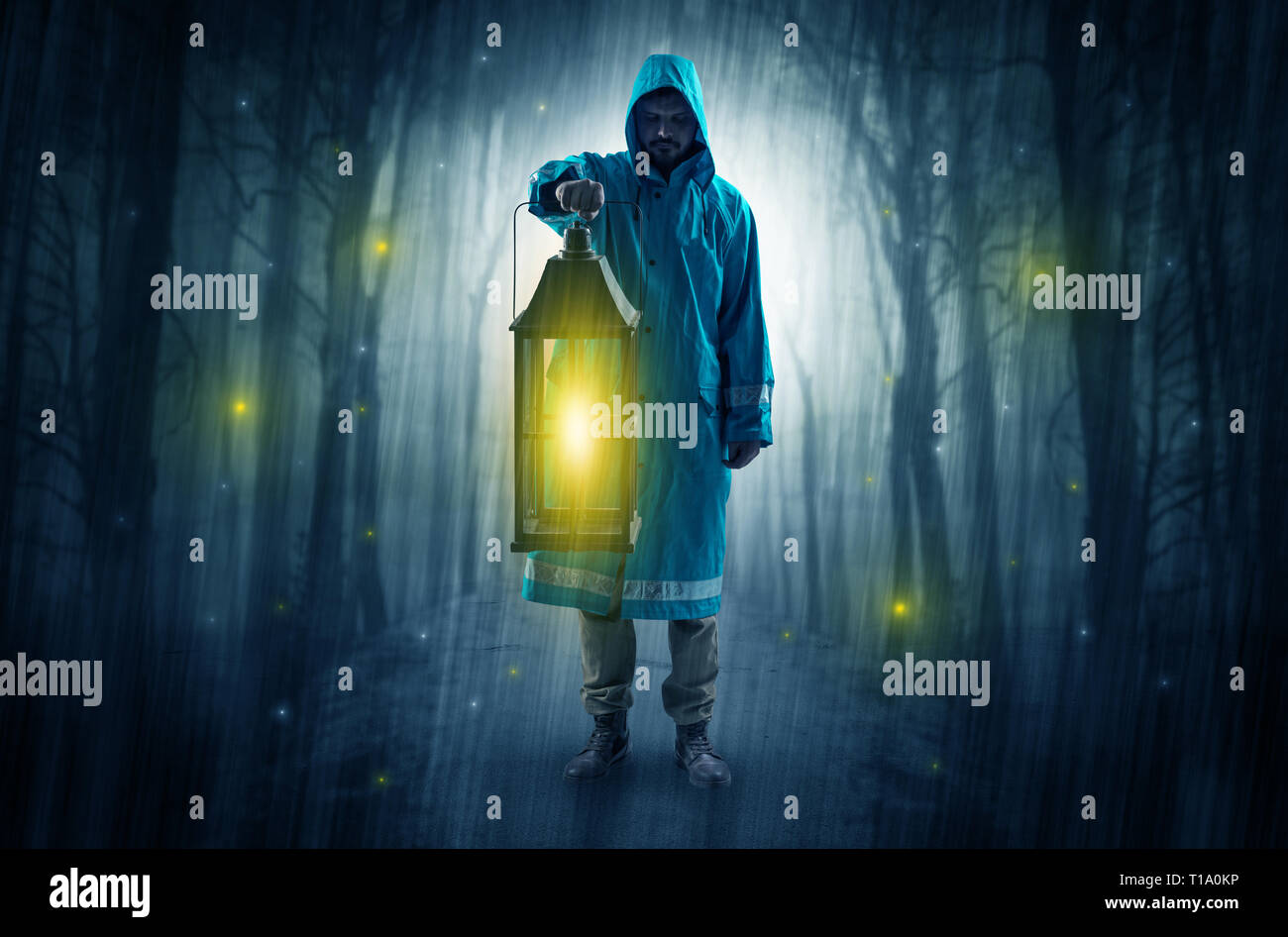 Man in raincoat coming from dark forest with glowing lantern in his ...