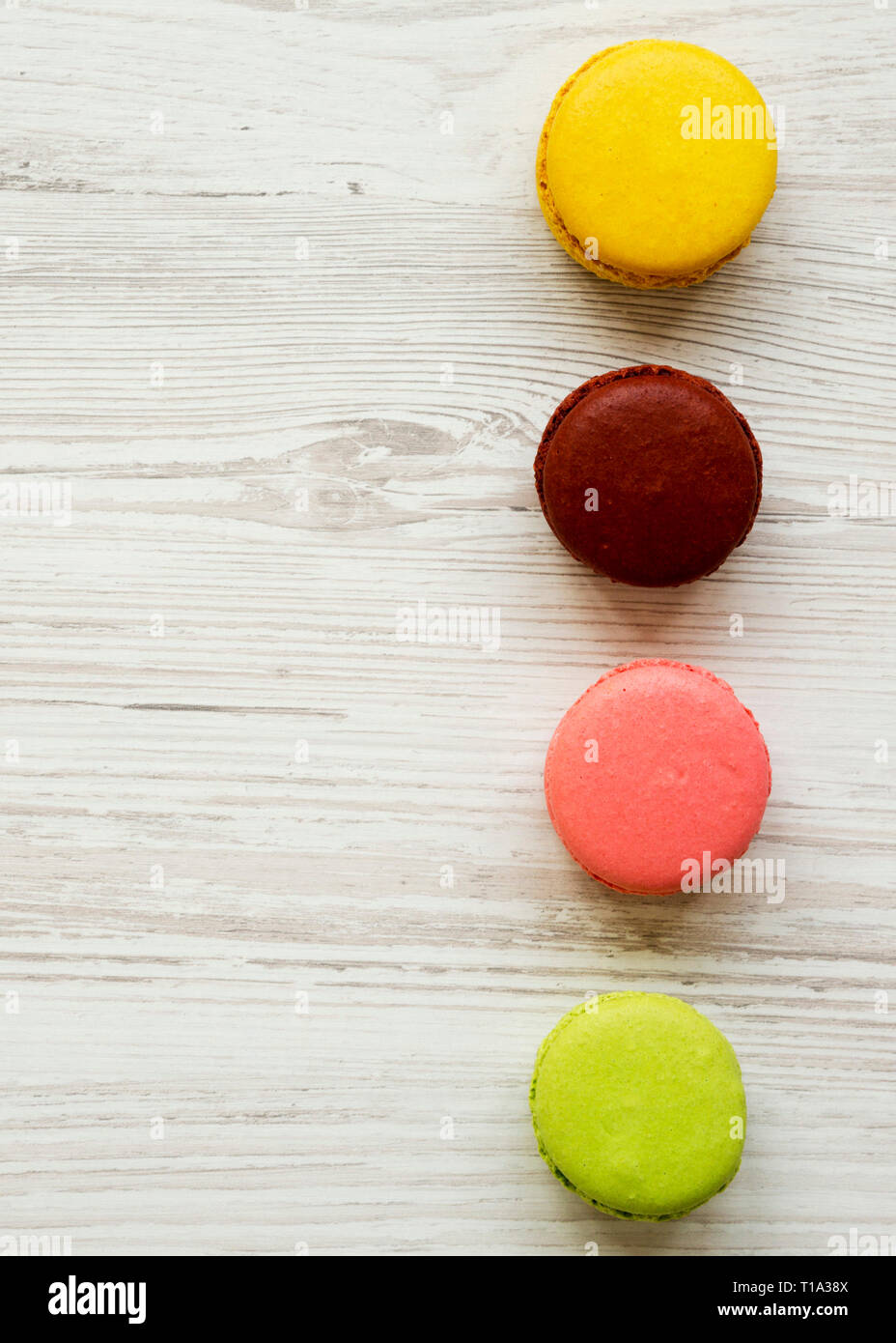 Colorful macarons on a white wooden table, overhead view. Flat lay ...