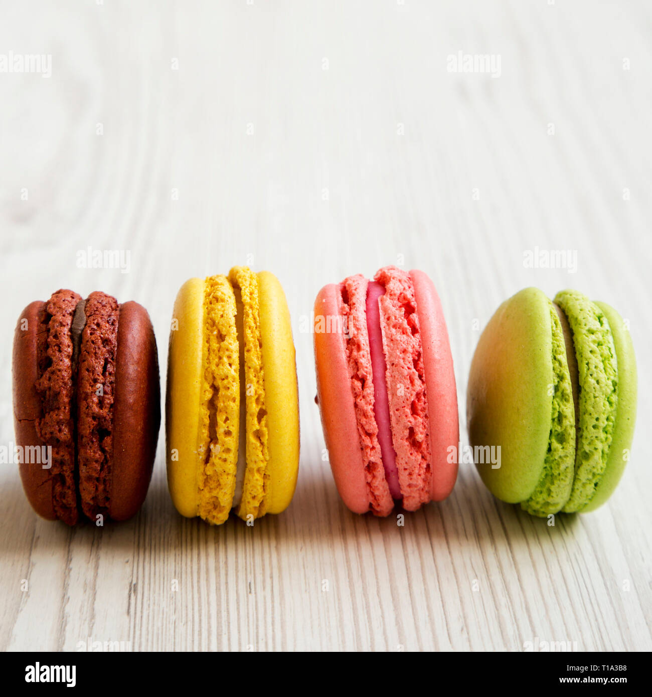 Sweet and colorful macarons on a white wooden background, side view ...