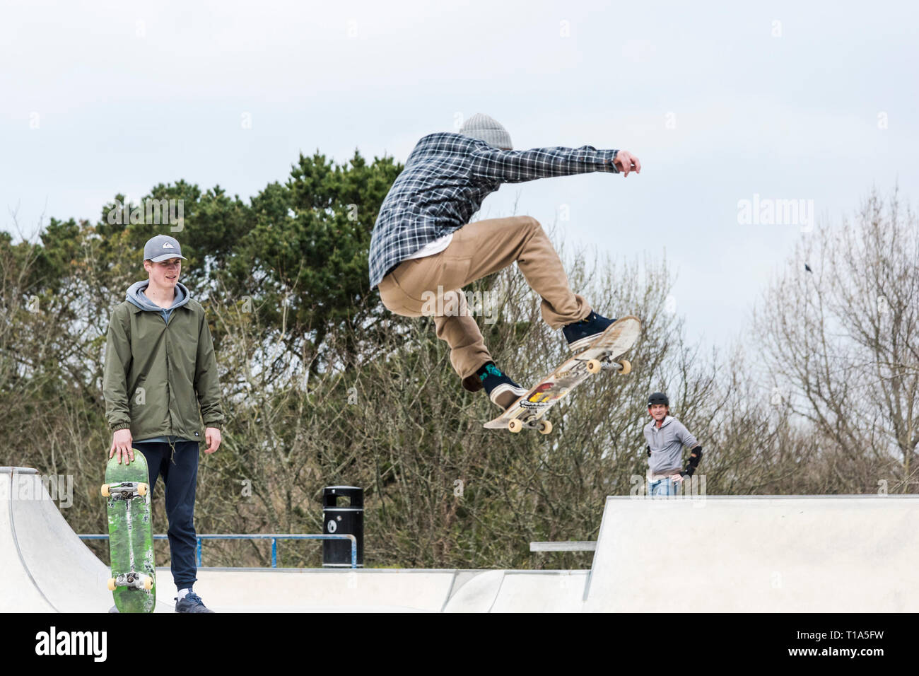 A skateboarder watching another skateboarder performing an aerial trick ...