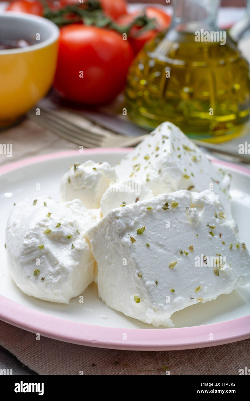 Fresh young soft white salted Feta cheese on plate seasoned with dried ...