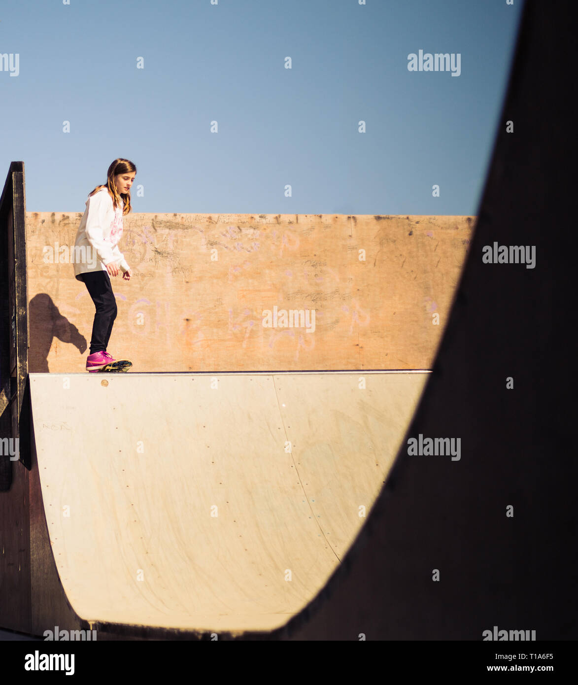 Beautiful teenage girl preparing to jump of the skate ramp on the skate ...