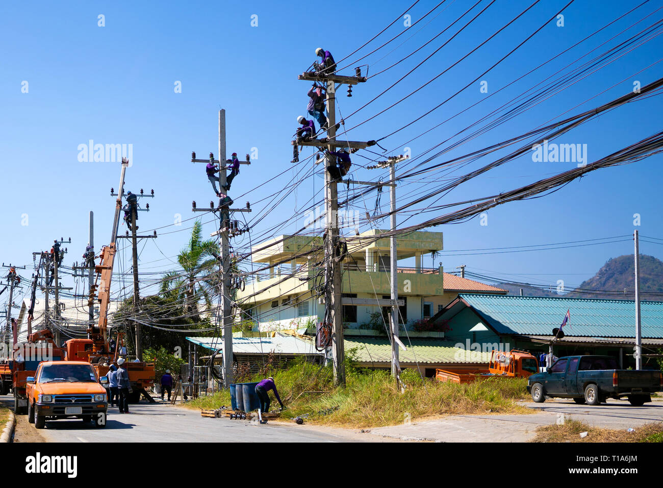Electricians working on a power pole, filled with complex communication ...