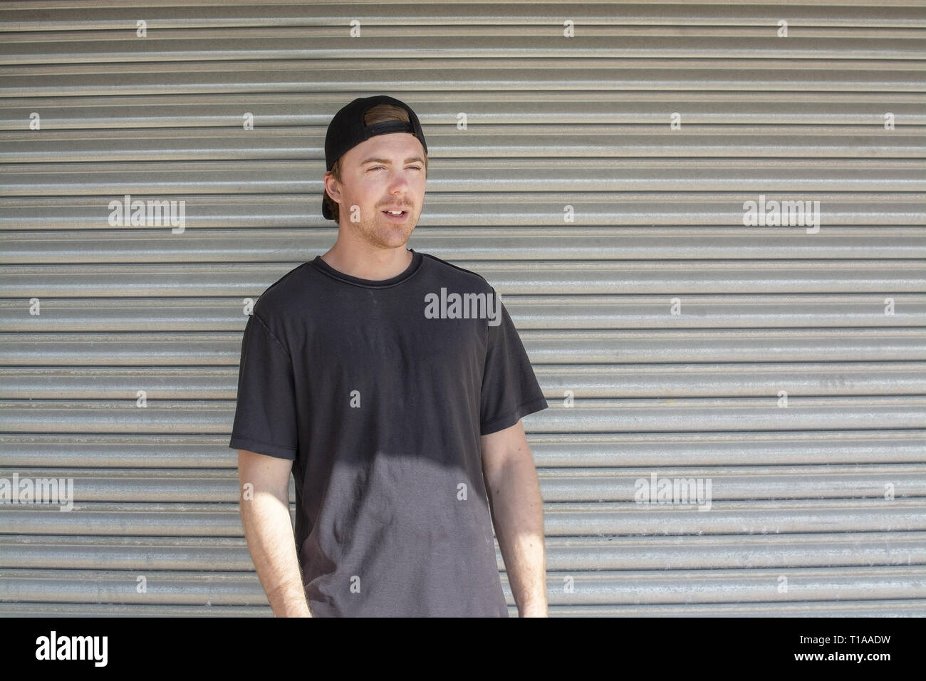 Young casual sporty dressed man with cap backwards in black against ...