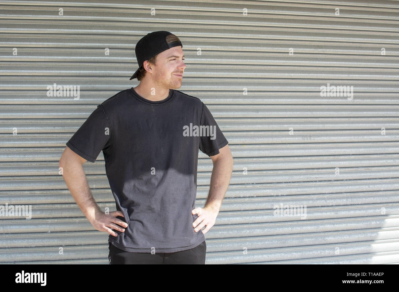 Young casual sporty dressed man with cap backwards in black against ...