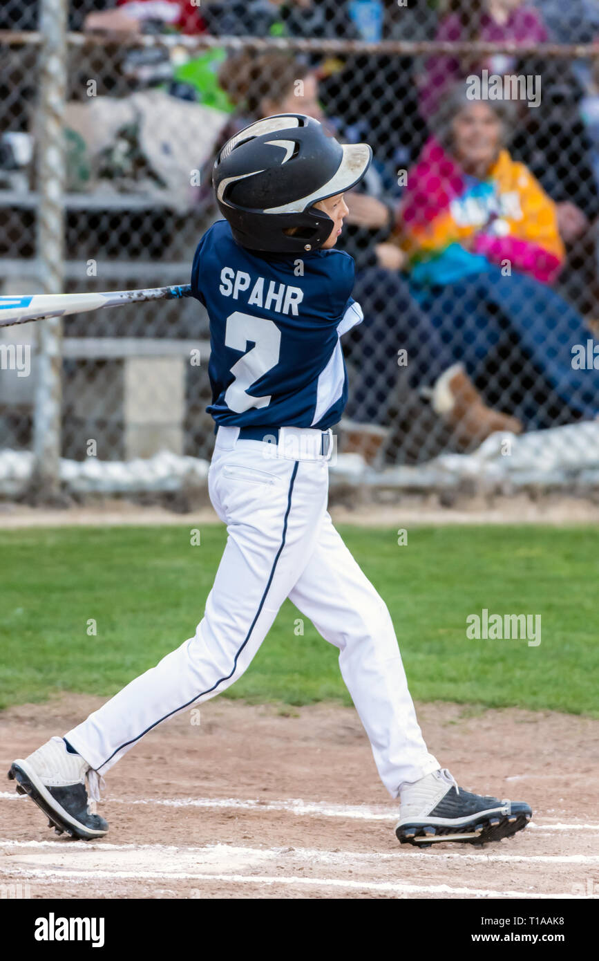 Little league batter twisting body while following through on big swing ...