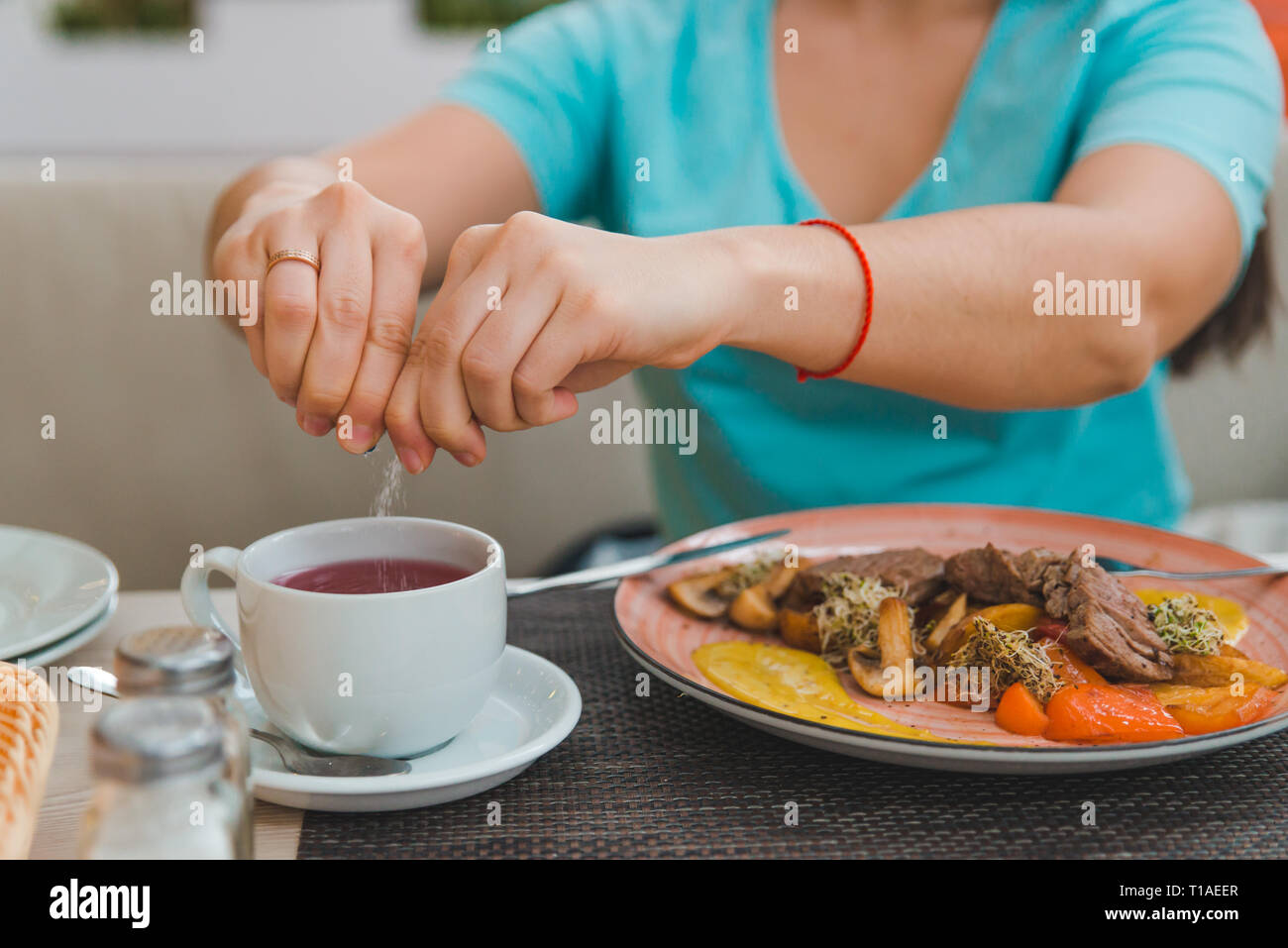 put sugar in cup of fruit tea. eating in cafe Stock Photo - Alamy