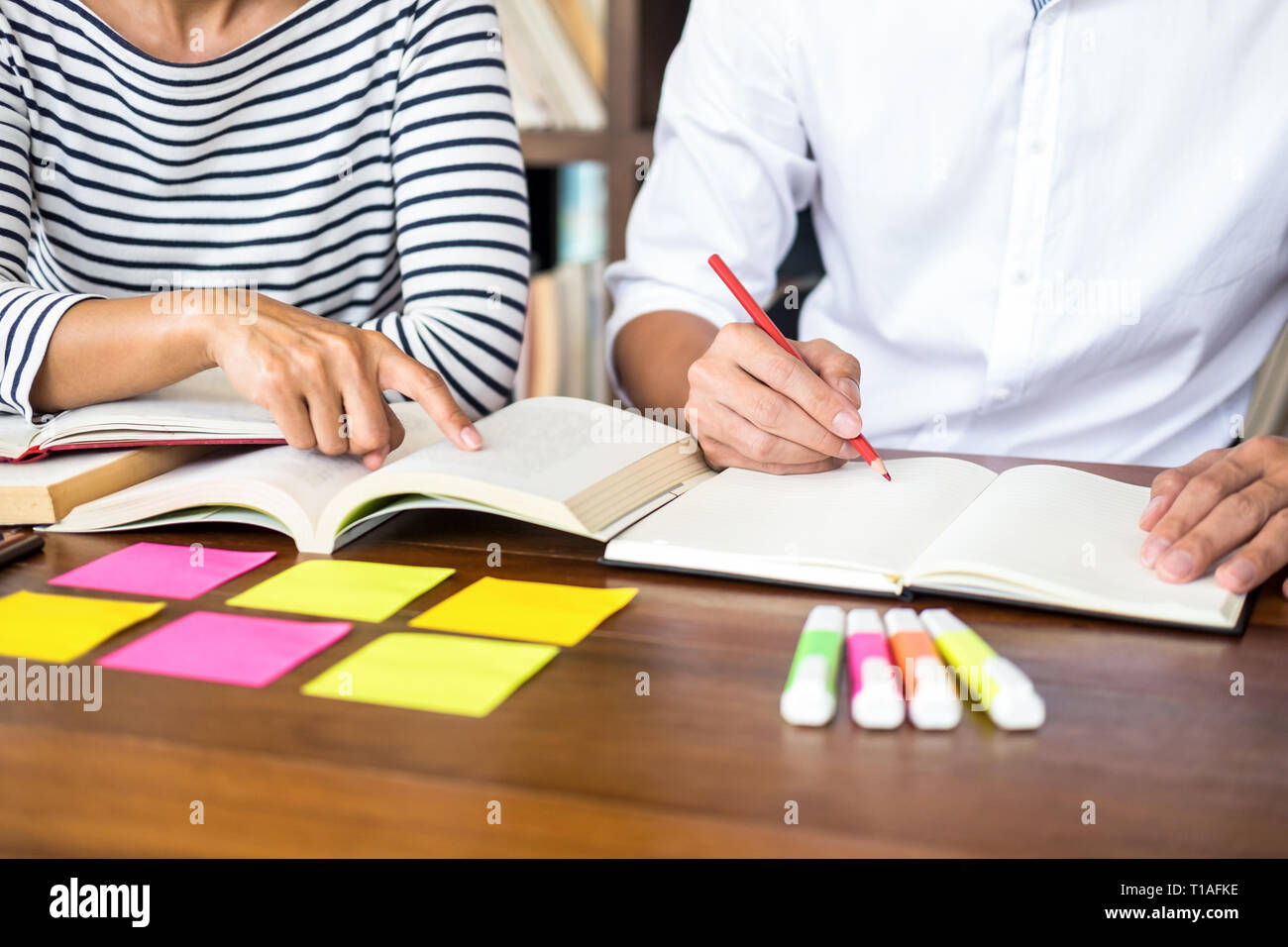 Young students classmates help friend catching up workbook and learning ...