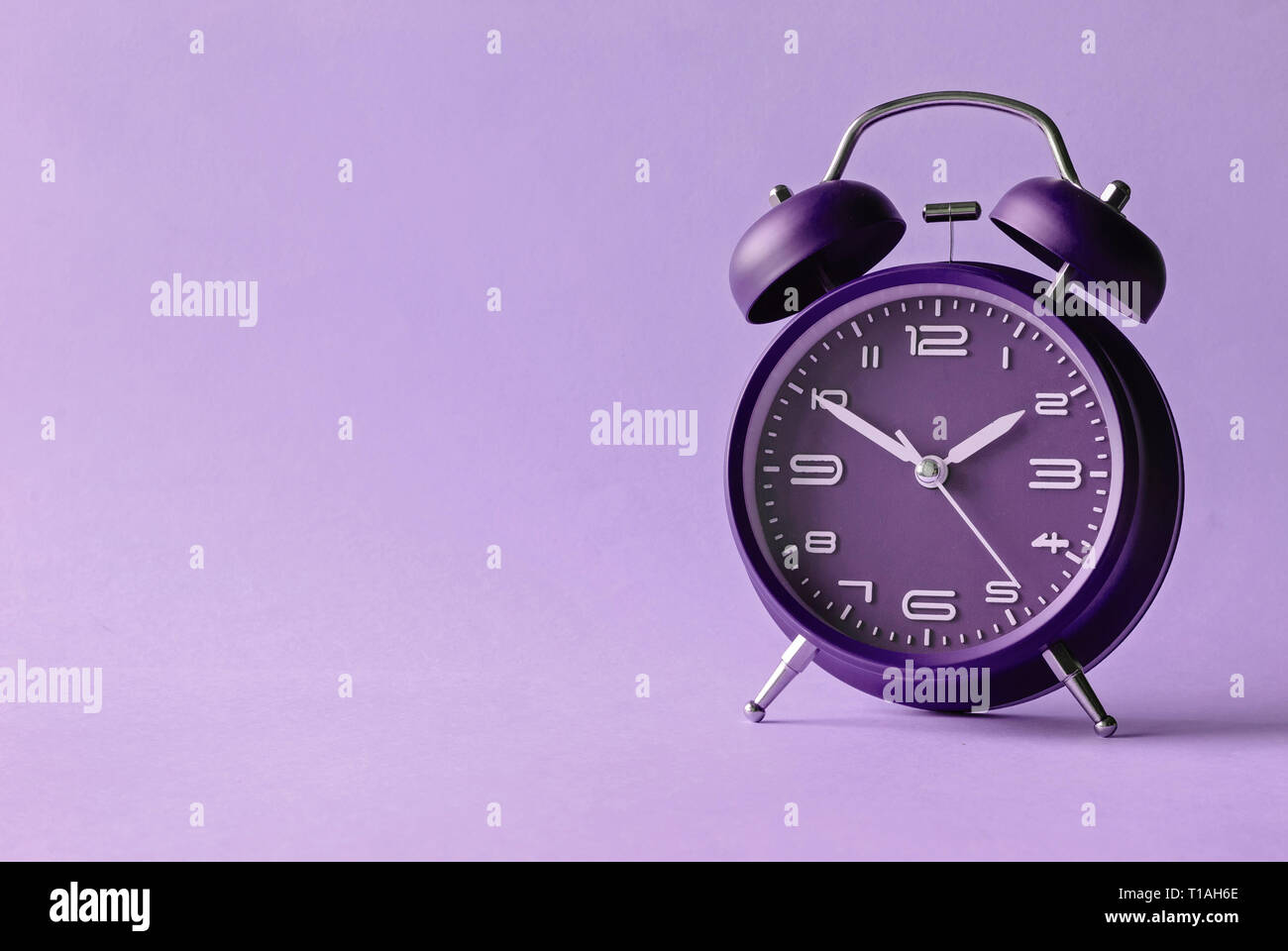 Old fashioned red alarm clock with bells centered over a violet ...