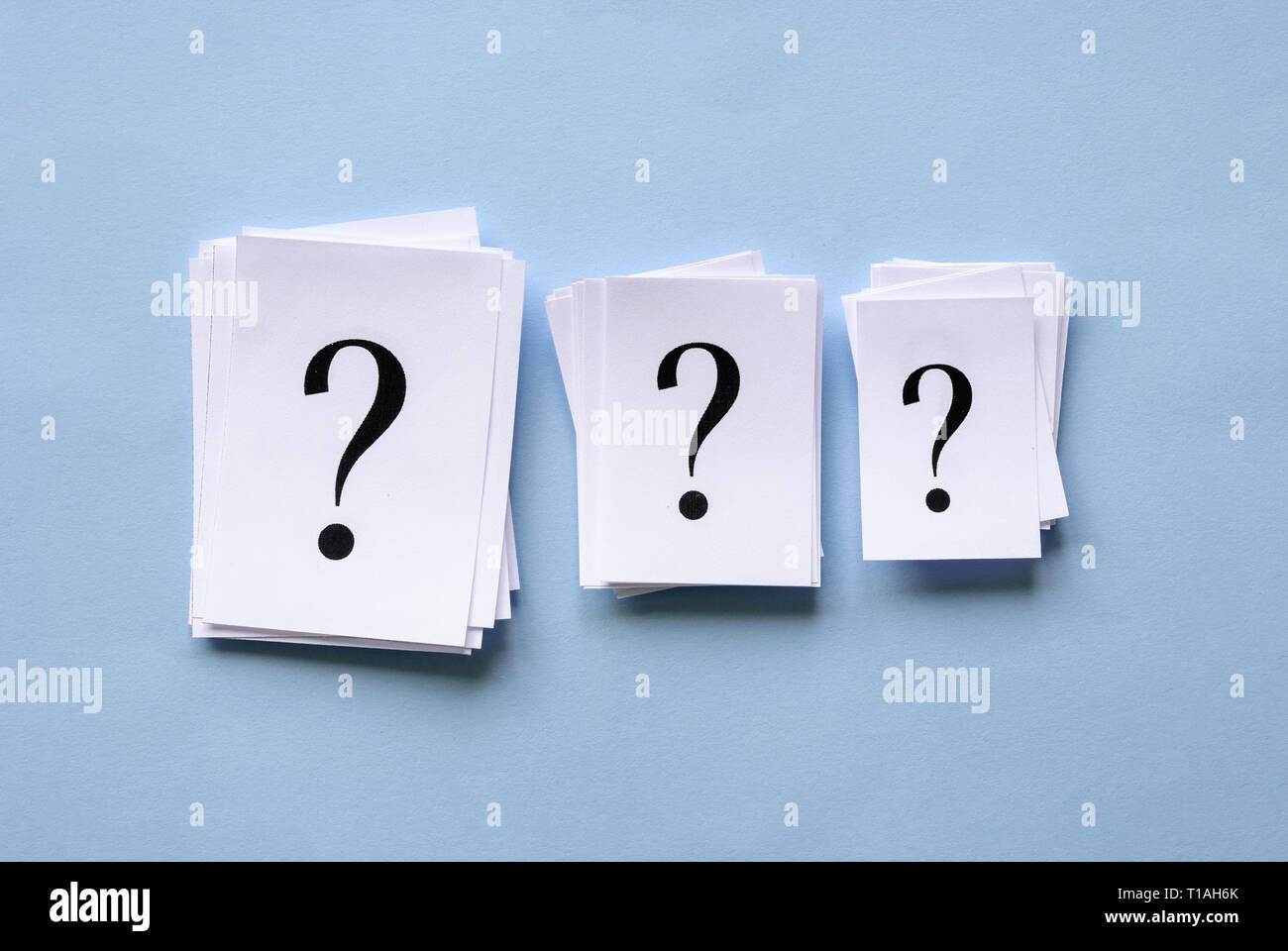 Three stacked heaps of paper with black question marks in descending ...