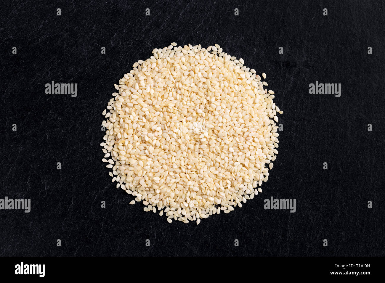 Circular heap of sesame seeds on black slate background, view from ...