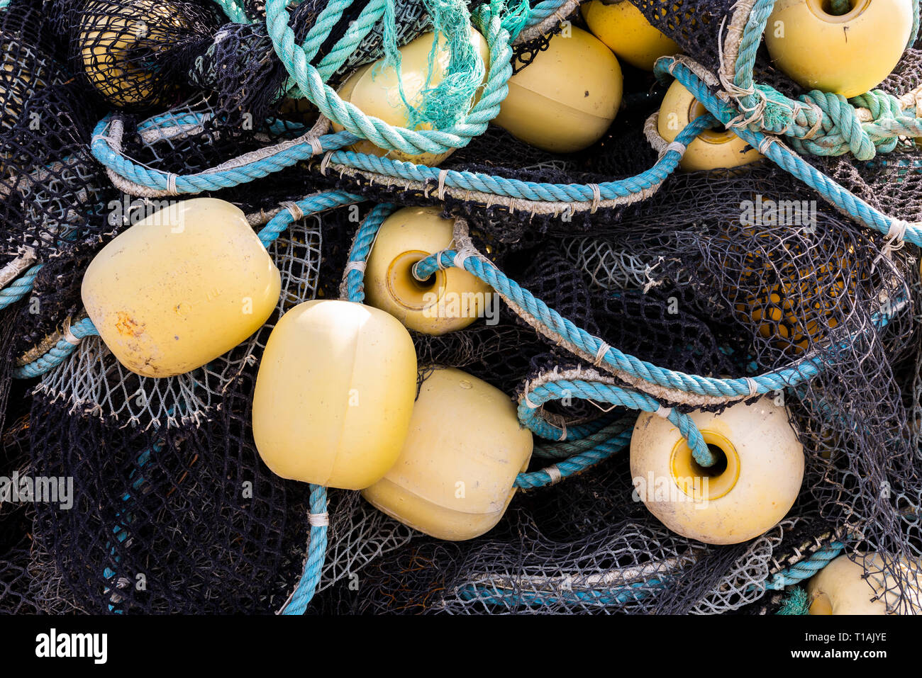 Black fishing net on the shore on a pile with yellow buoys in a harbor ...