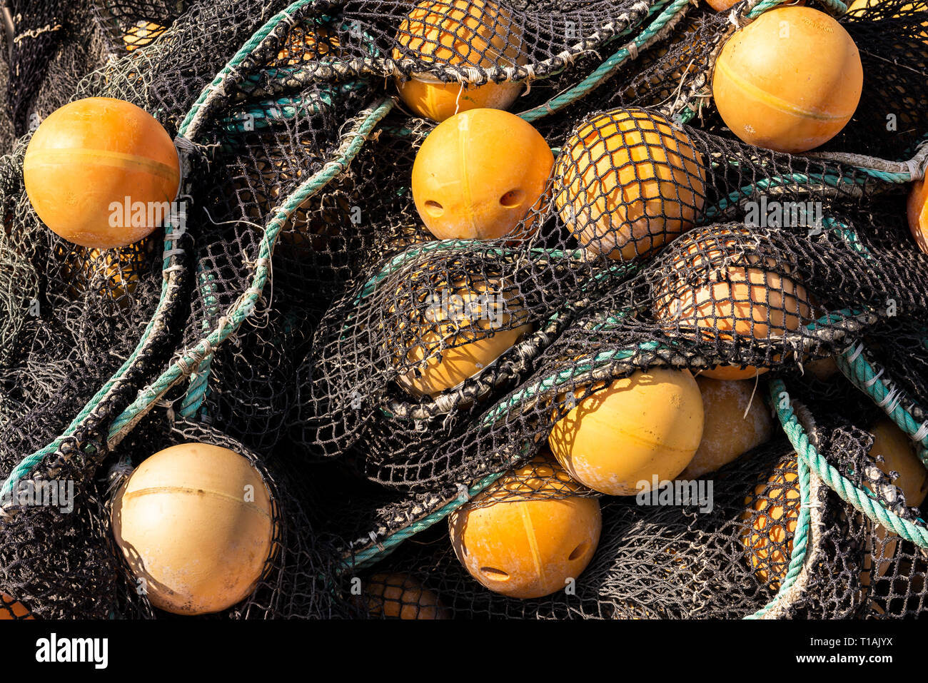 Black fishing net on the shore on a pile with orange buoys Stock Photo ...