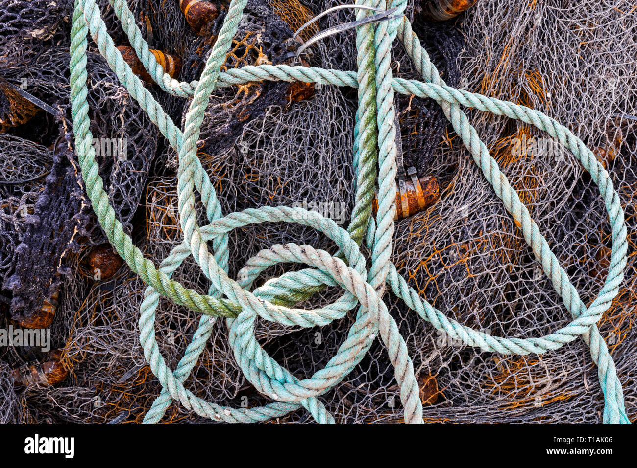 Black fishing net on the shore on a pile with blue rope in a harbor in ...