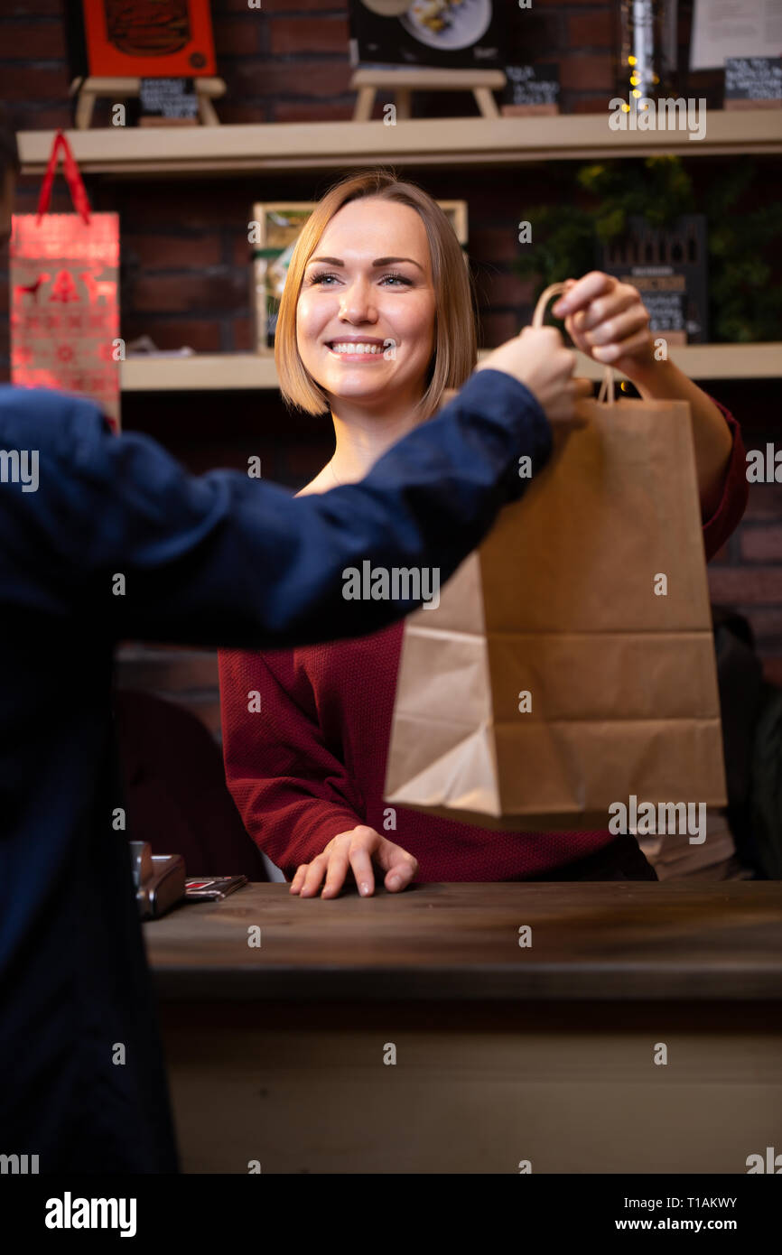 Image of smiling seller blonde giving paper bag to man Stock Photo - Alamy