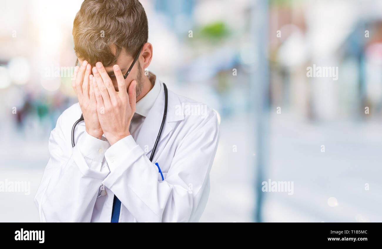 Young doctor man wearing hospital coat over isolated background with ...