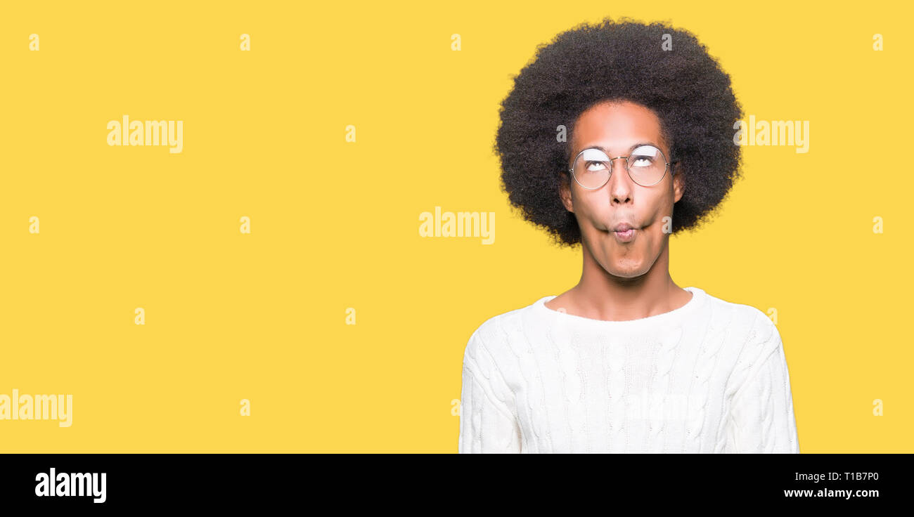 Young african american man with afro hair wearing glasses making fish ...