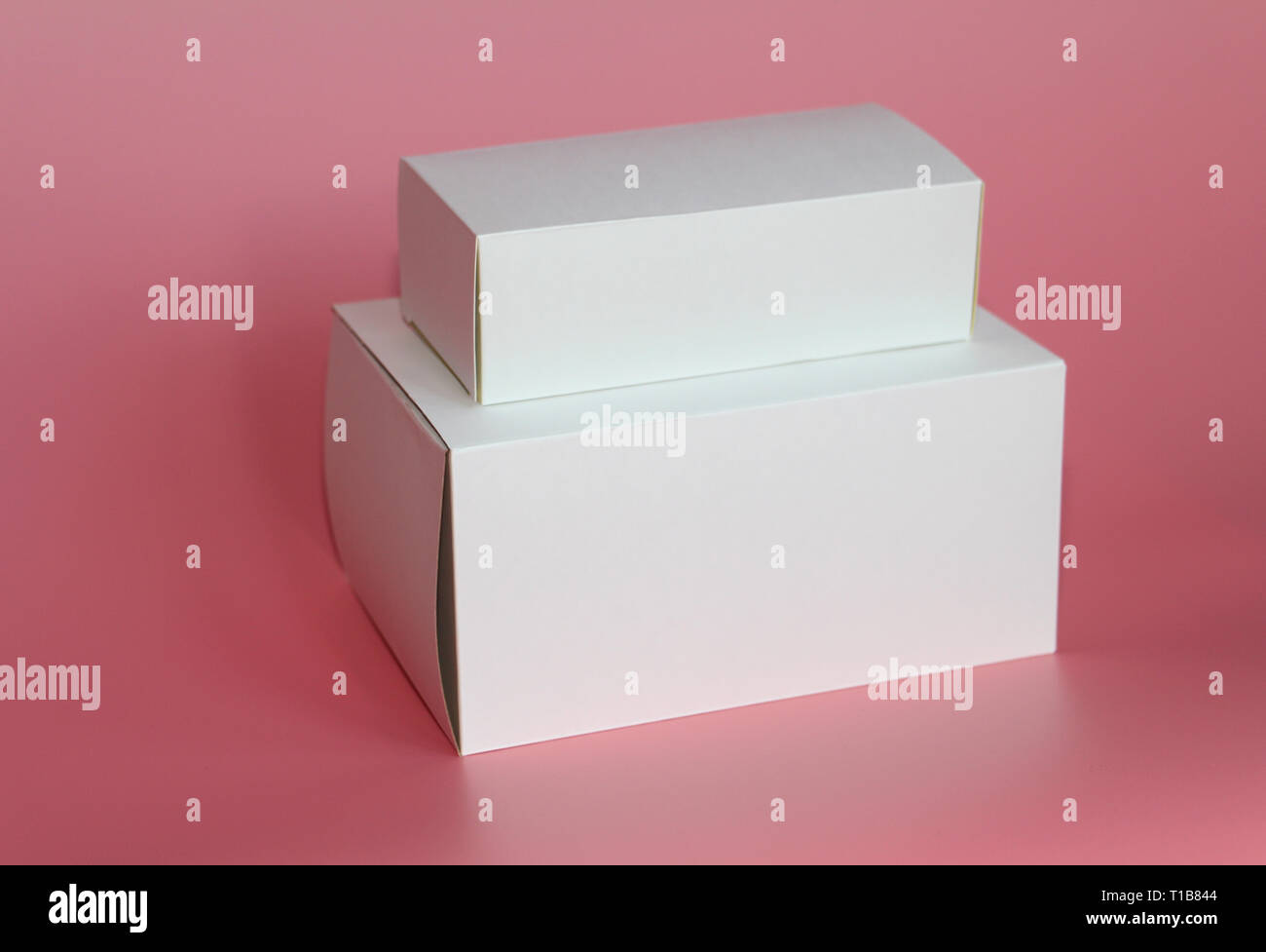 Two white boxes on a pink background. The boxes are on top of each ...