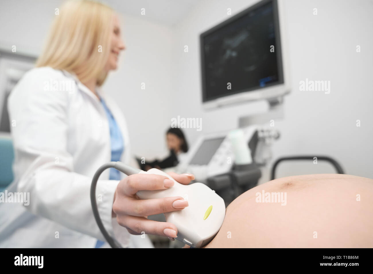 Close up of pregnant abdomen of woman and doctor doing ultrasound ...