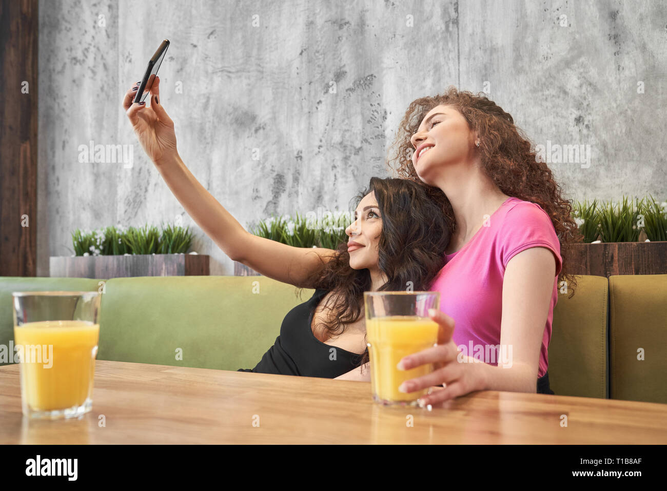 Two joyful young girls with beautiful curly hair hanging out together ...