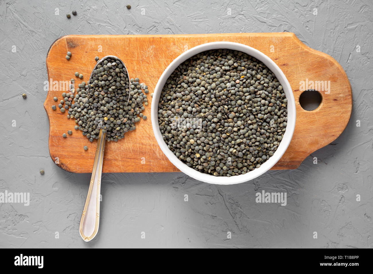 Dry green french lentils on rustic wooden board over concrete ...