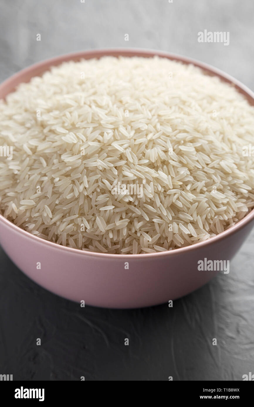 Dry white rice basmati in a pink bowl over concrete background, side ...