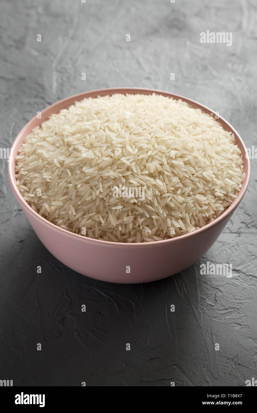 Dry white rice basmati in a pink bowl over gray background, side view ...