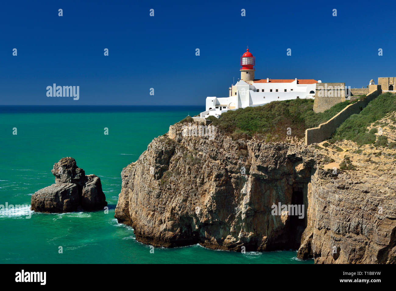 Lateral view of red lighthouse with white washed building on rocky ...