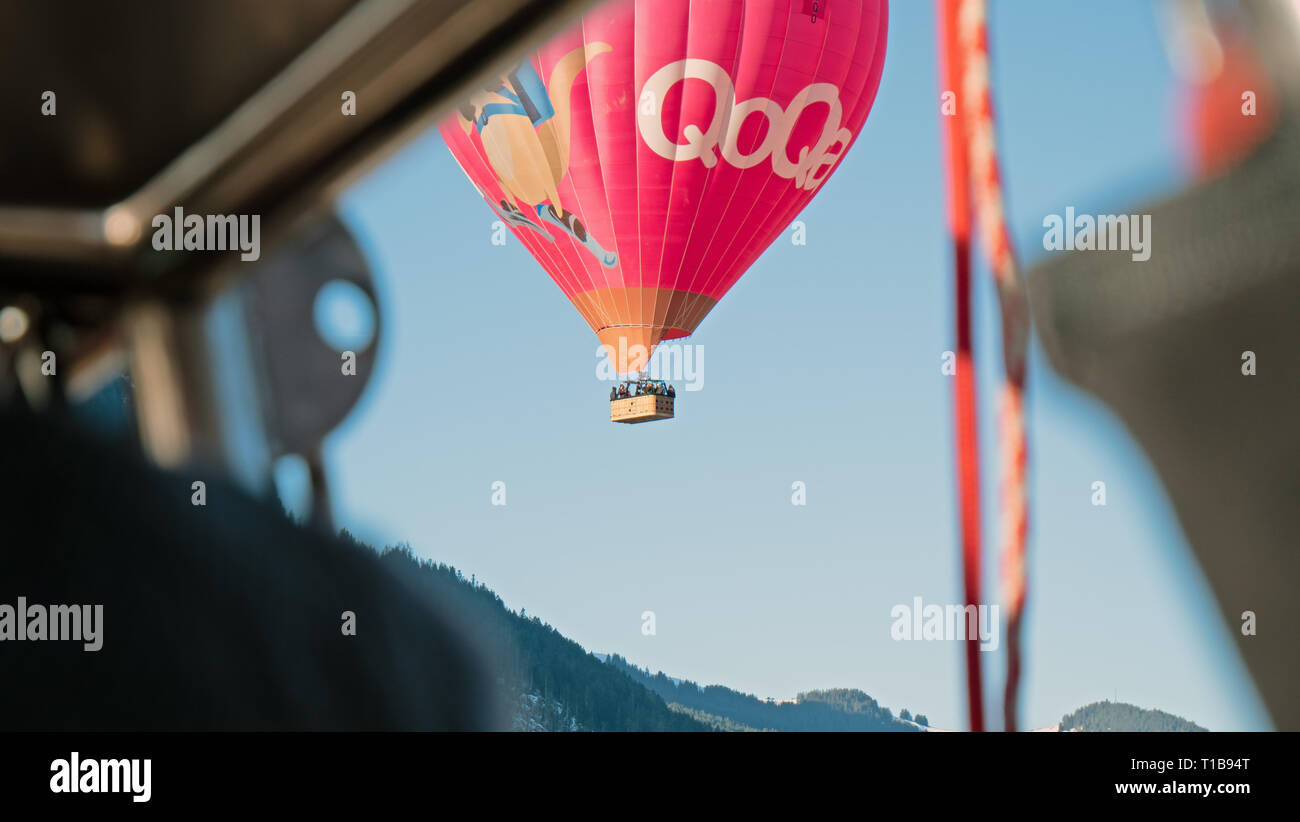 A hot air balloon takes a flight over the high snow covered peaks of ...