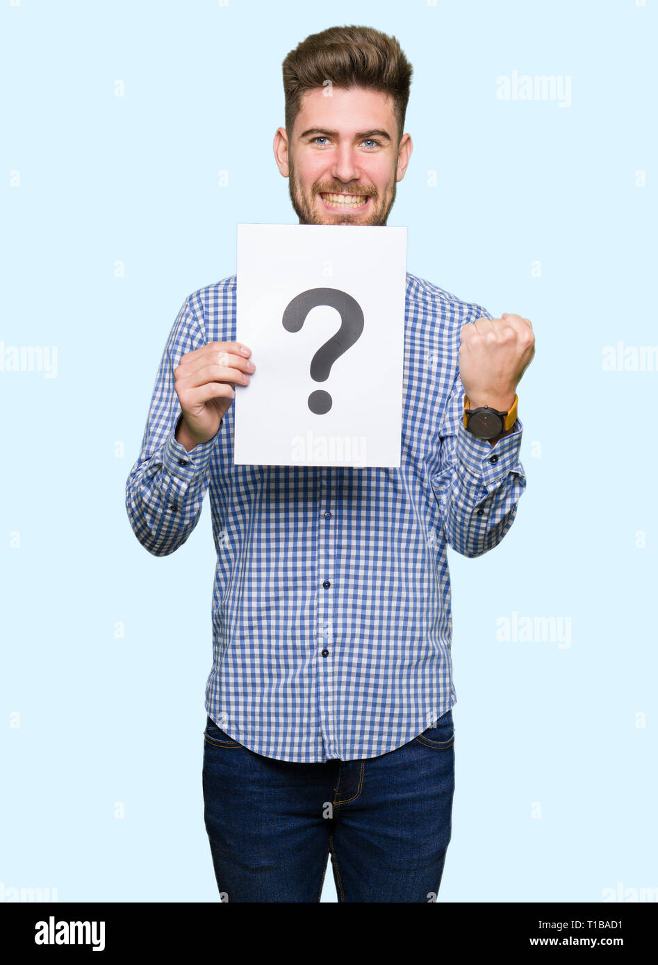 Young handsome man holding paper with question mark screaming proud and ...