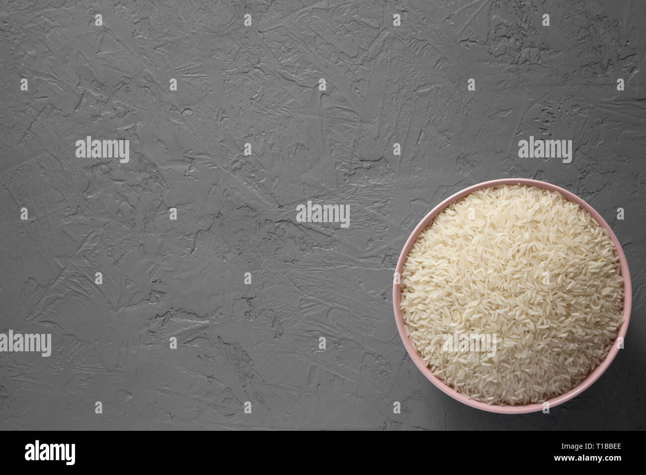 Dry white rice basmati in a pink bowl over concrete background, top ...